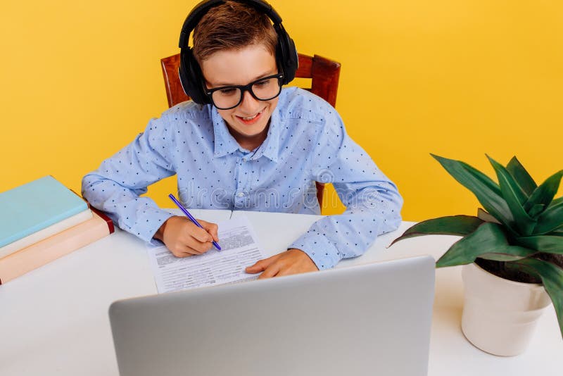 Focused Schoolboy Guy in Headphones, Doing Homework Using a Laptop ...