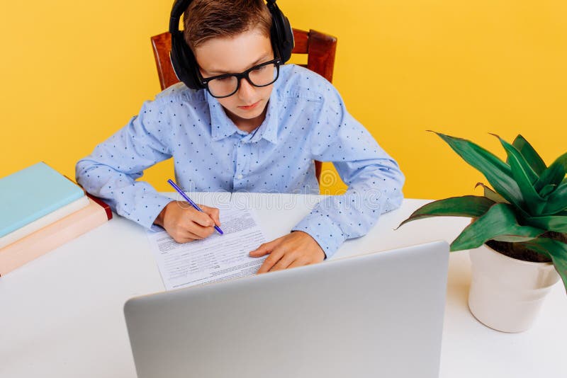 Focused Schoolboy Guy in Headphones, Doing Homework Using a Laptop ...