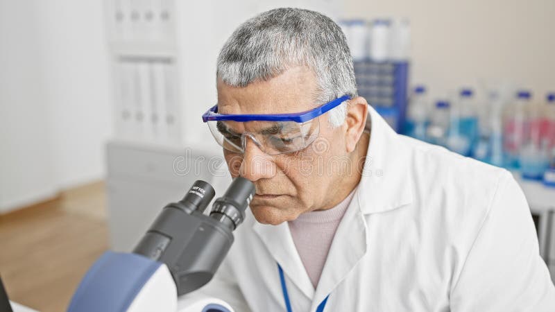Focused Senior Man Examining Samples Under a Microscope in a Modern ...