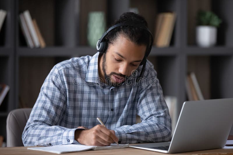 Focused Student Guy in Headphones with Mic Writing Notes Stock Photo ...