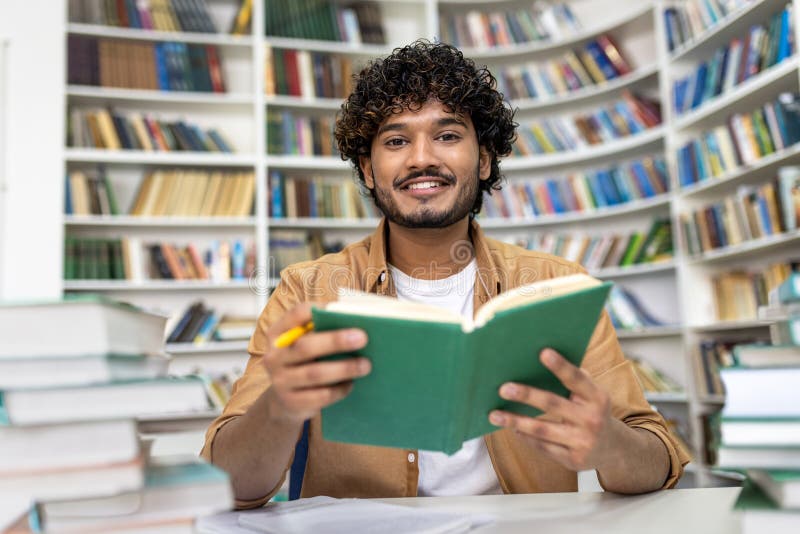 Focused Student Studying in a Library Surrounded by Books and Preparing ...