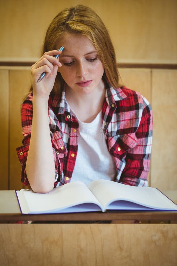 Focused Student Leaning Against Bookshelves and Reading a Book in ...