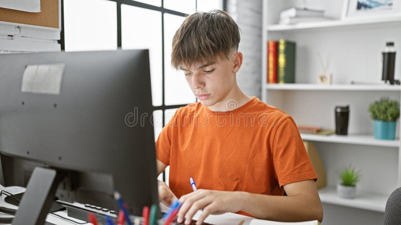 Focused Teenage Boy Studying at a Modern Home Desk Setup, with a ...
