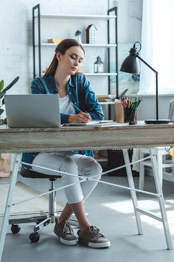 Focused Teenage Girl Taking Notes and Using Laptop while Studying Stock ...