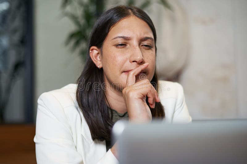 Focused Woman Deep in Thought while Looking at Laptop in Modern Office ...