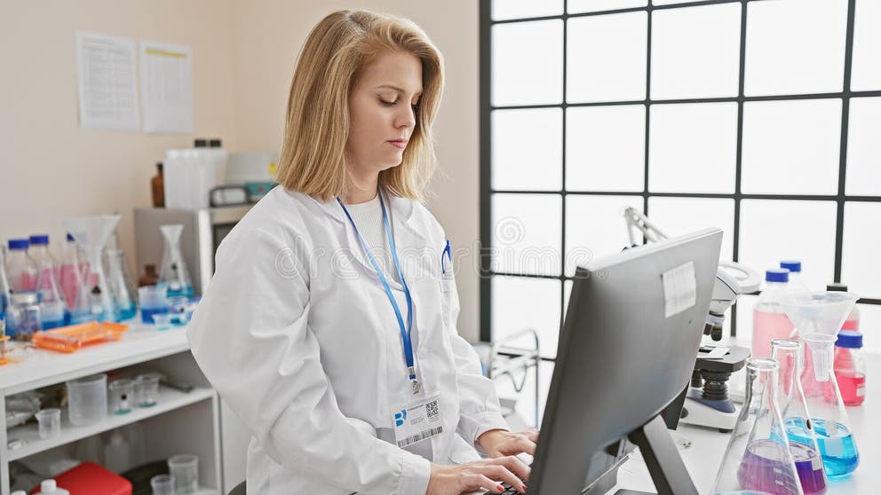 Focused Woman Scientist Using Computer in Modern Laboratory with ...