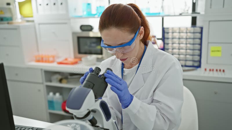 A Focused Woman Scientist Using a Microscope in a Laboratory Setting ...