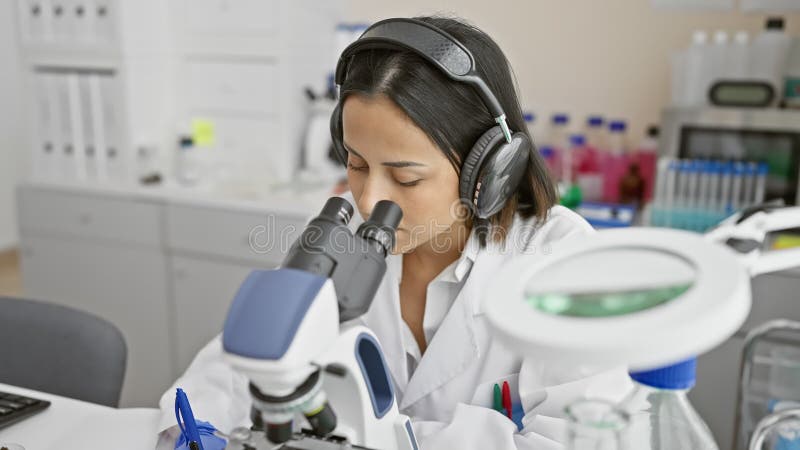 A Focused Woman Scientist Using a Microscope in a Laboratory Setting ...