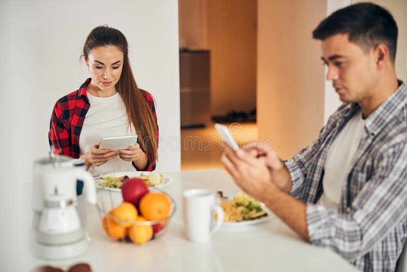 Young Couple Browsing the Web on Their Gadgets Stock Photo - Image of ...