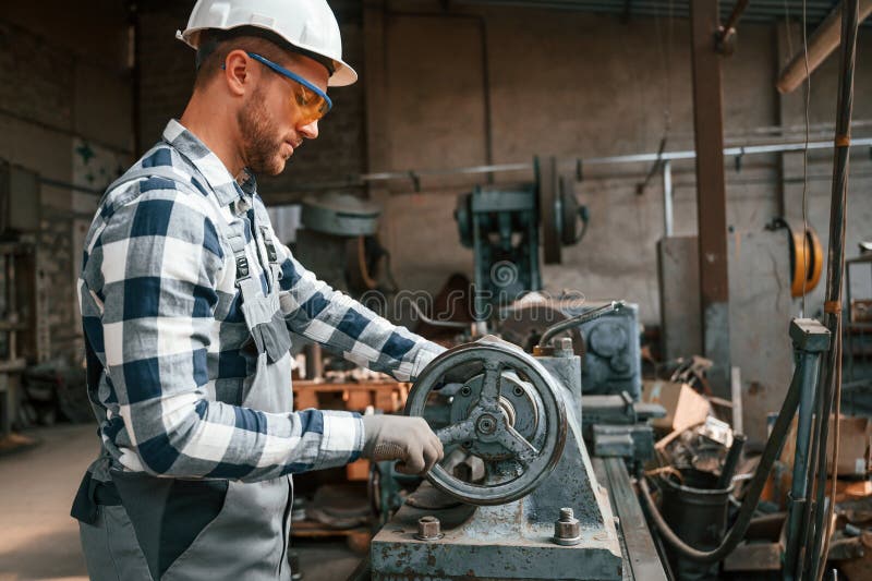 Focused on Work with Factory Machine. Worker in Uniform is Indoors ...