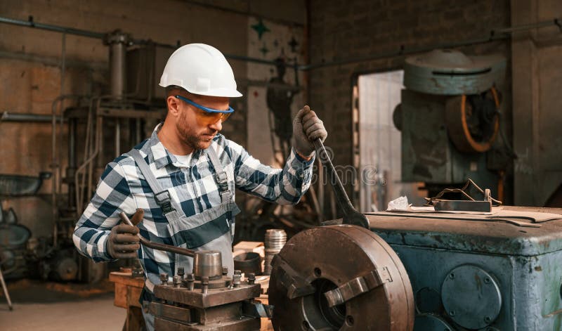 Focused on Work with Factory Machine. Worker in Uniform is Indoors ...