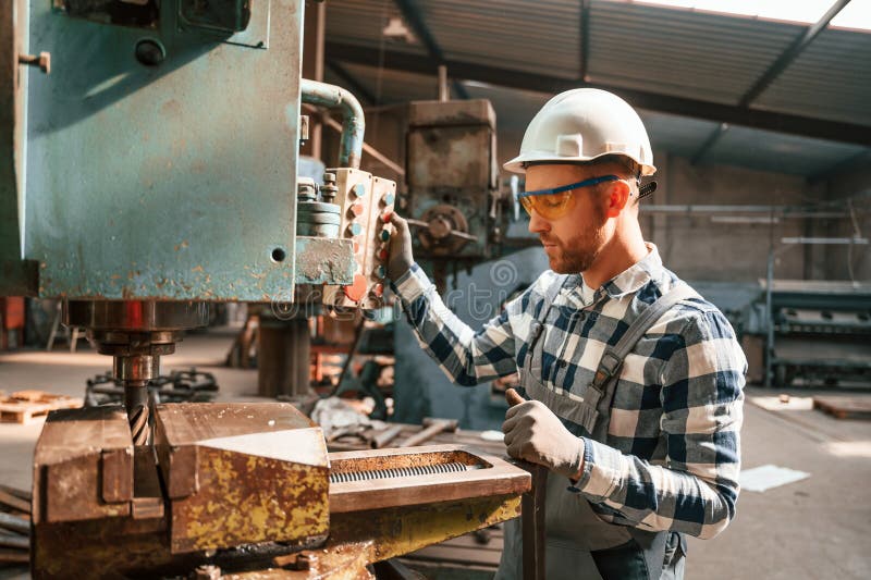 Focused on Work with Factory Machine. Worker in Uniform is Indoors ...
