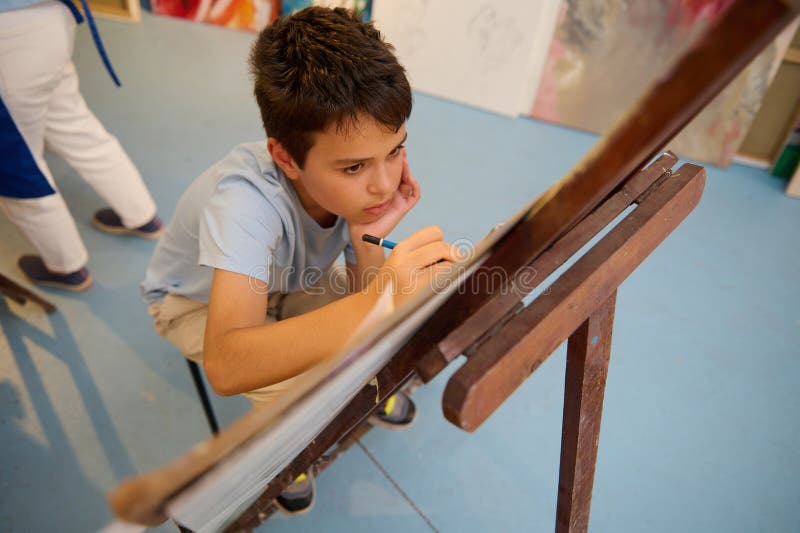 Focused Young Boy Drawing on Easel during an Engaging Art Class ...