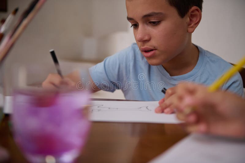 Focused Young Boy Engaged in Drawing and Writing at a Wooden Table ...