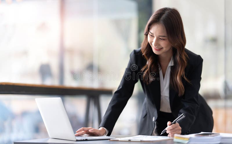 Focused Young Businesswoman Standing at Table in Office, Using Laptop ...