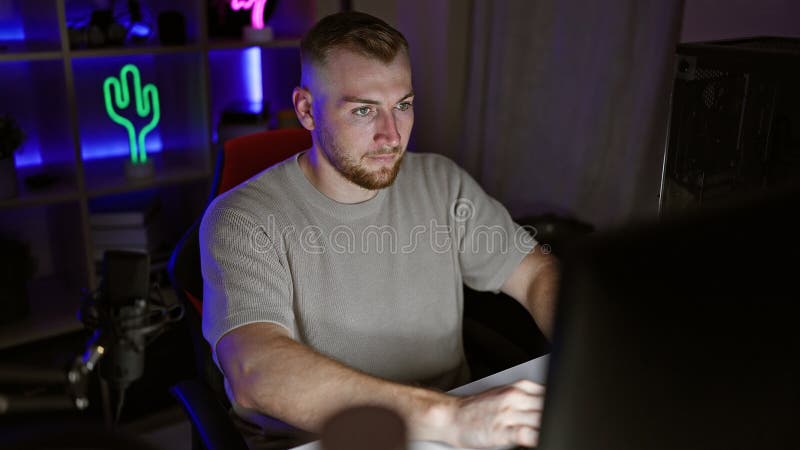 A Focused Young Man with a Beard Works on a Computer in a Dark, Neon ...
