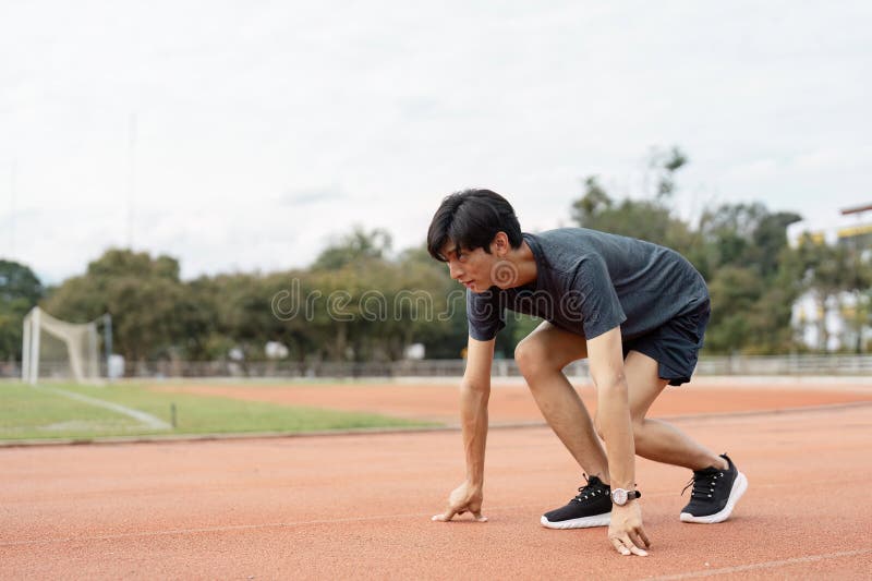 Determined Young Man Preparing To Sprint on a Track, Focused on His ...
