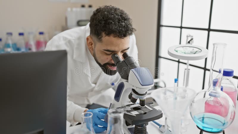 A Focused Young Man Examining Substances Under a Microscope in a Modern ...