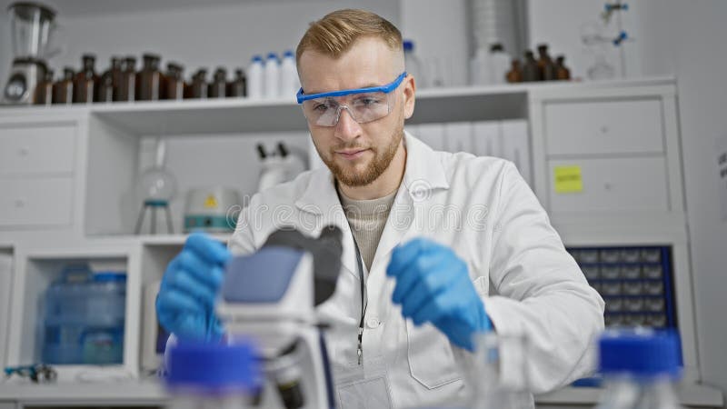 A Focused Young Man in Lab Coat Conducts Experiments in a Modern ...