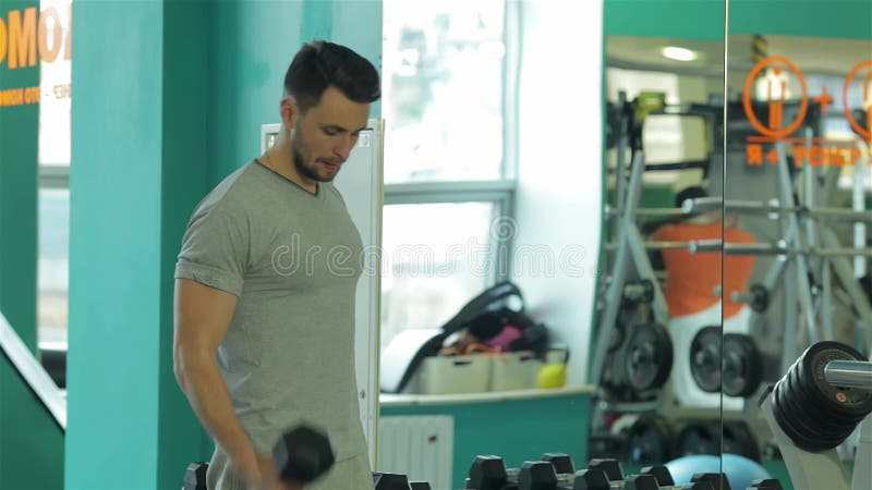 Focused Young Man Lifting Dumbbells while Observing His Reflection in ...