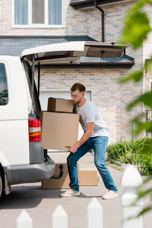 Focused Young Man Moving Boxes from Car into New Stock Photo - Image of ...