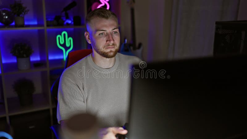 Focused Young Man Using Computer in a Dark Gaming Room with Neon Lights ...