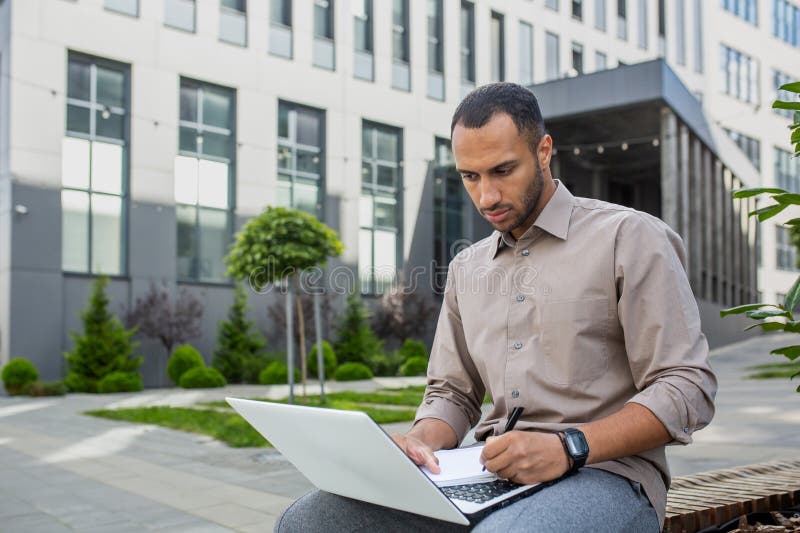 Focused Young Businessman Working on Laptop while Sitting Outdoors in ...