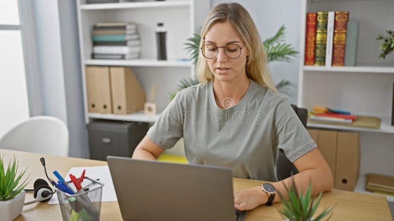 A Focused Young Woman Working on a Laptop in a Modern Office Setting ...