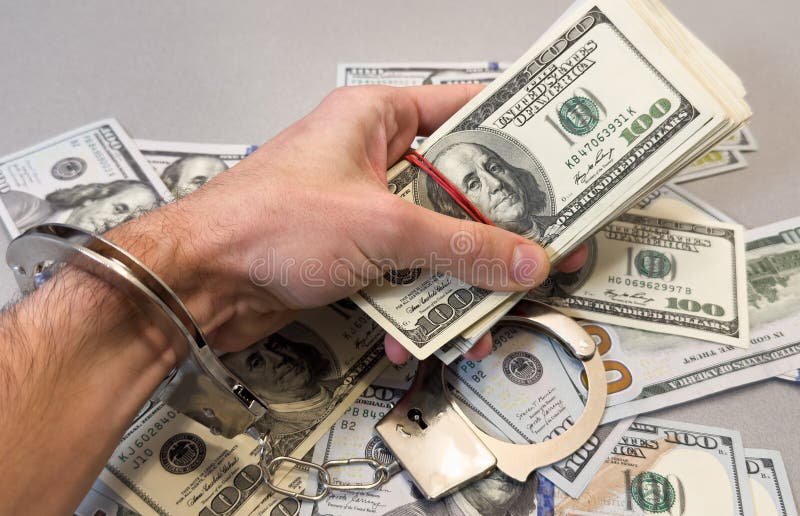 Folded Hands and Handcuffed Hands Resting on a Table in Front of Money ...