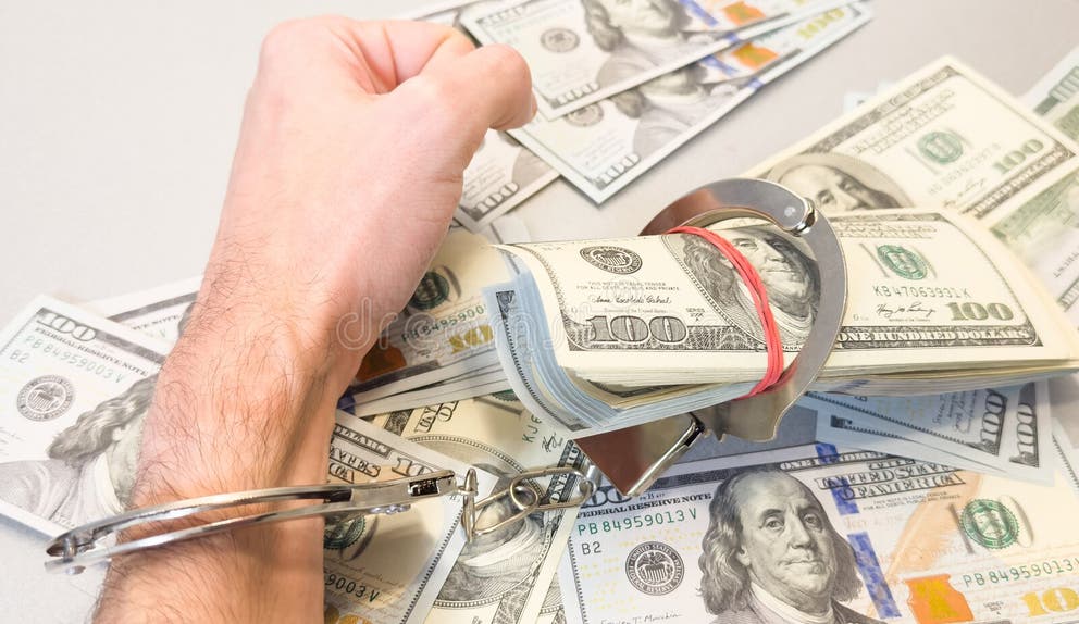 Folded Hands and Handcuffed Hands Resting on a Table in Front of Money ...