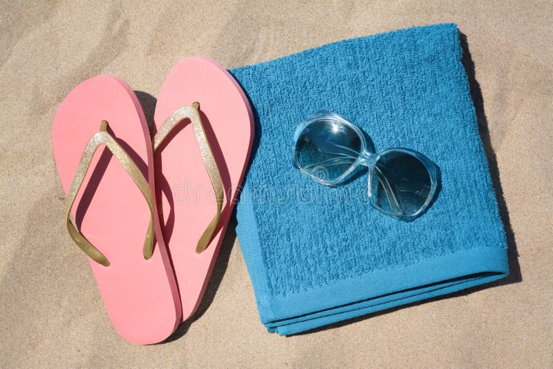 Folded Soft Blue Beach Towel with Flip Flops and Sunglasses on Sand ...