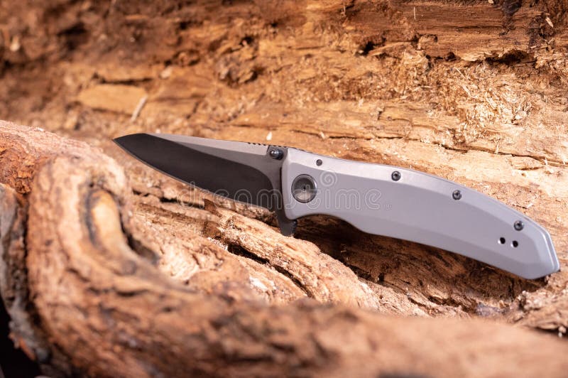 Folding Knife with Aluminum Handle and Black Blade. Knife on a Wooden ...