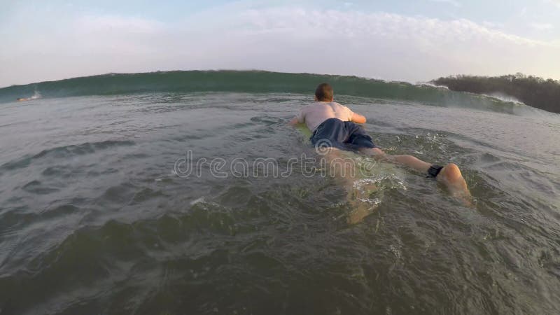 A Man on a Surfboard Swims Out into the Ocean Under a Wave Stock Video ...