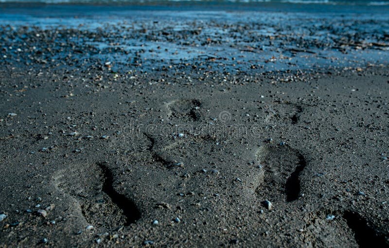 Footprints on black sand stock image. Image of volcanic - 322604575