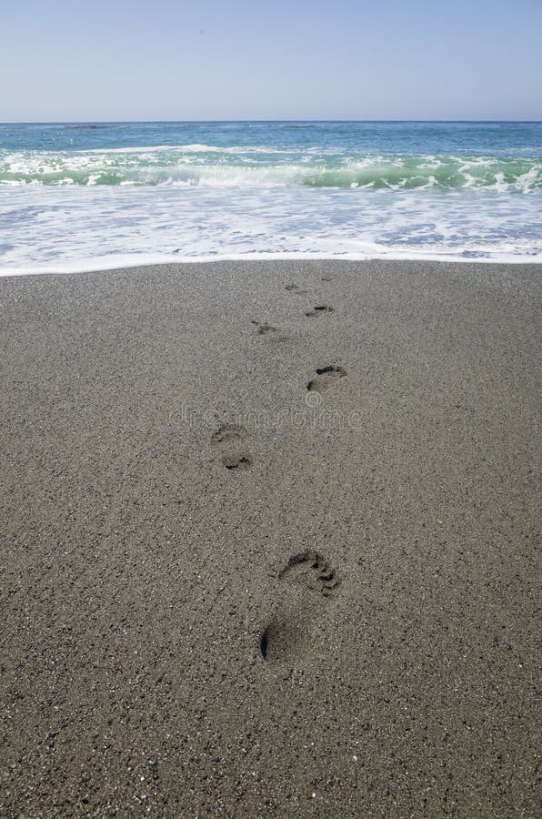 Footprints on a Grey Beach Walking into the Blue Ocean with Waves Stock ...