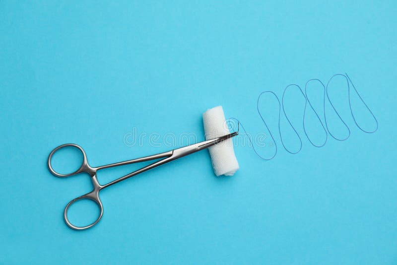 Forceps with Suture Thread and Bandage Roll on Light Blue Background ...