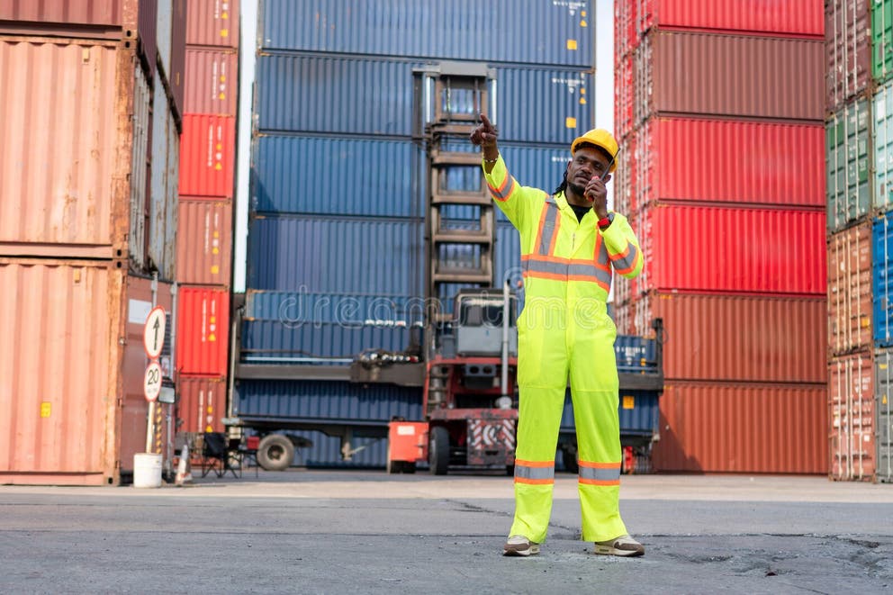 Foreman Dock Worker in Hardhat and Safety Vest Talks on Two-way Radio Control Loading Containers ...