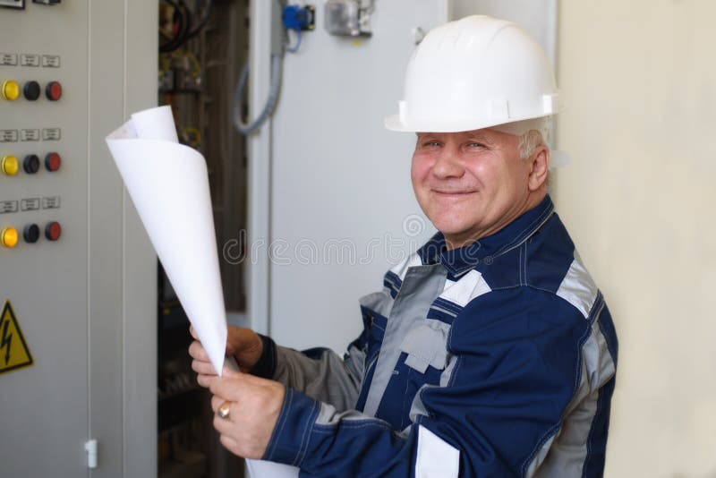 Foreman Electrician Examines the Working Draft Next To the Dashboard ...