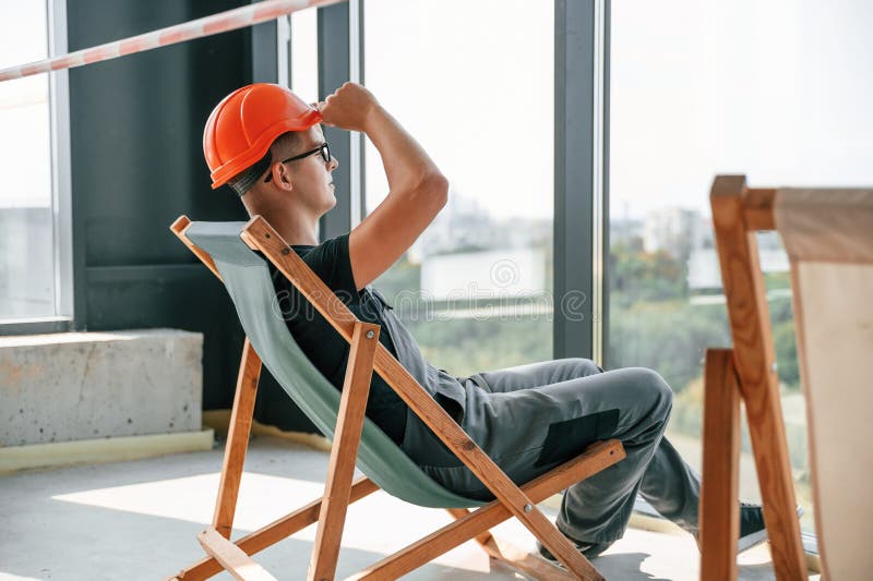 Foreman in Hard Hat and Uniform is Sitting, Looking at the View through ...