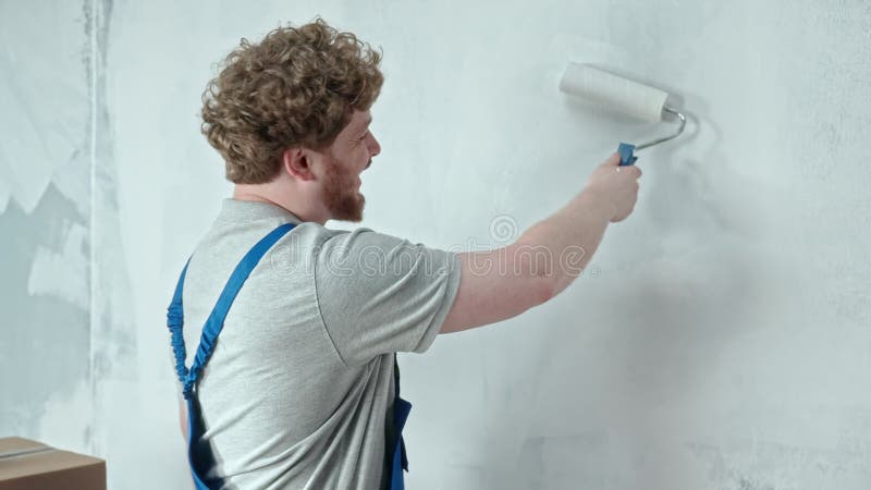 Foreman or Painter in Blue Construction Overalls is Painting Wall with ...