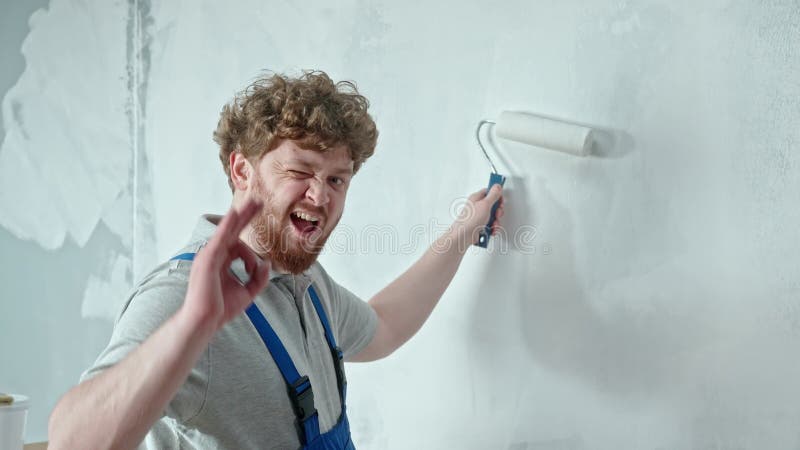 Foreman or Painter in Blue Construction Overalls is Painting Wall with ...