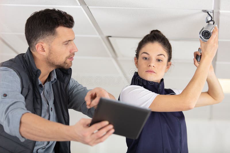Foreman Shows Tablet Screen To Female Apprentice Installing Cctv Camera ...