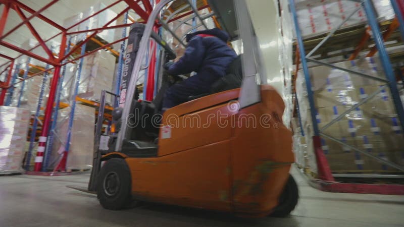 A Forklift is Driving through a Large Warehouse. Moving through a ...