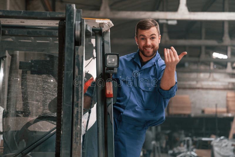With the Forklift. Factory Worker in Blue Uniform is Indoors Stock ...