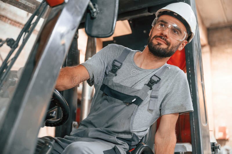 In the Forklift. Young Factory Worker in Grey Uniform Stock Photo ...