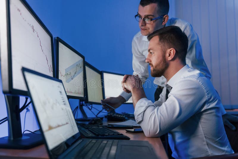 Analizing Graphs Together. Two Stock Traders Working in the Office with ...