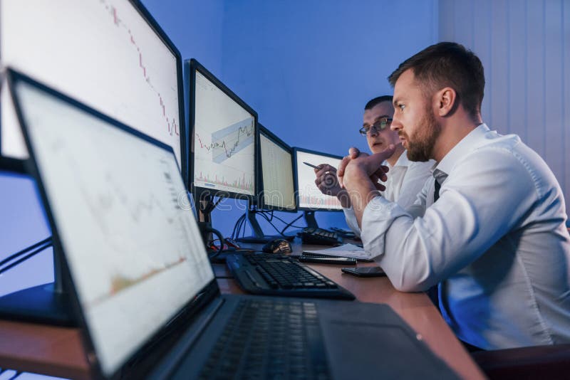 Analizing Graphs Together. Two Stock Traders Working in the Office with ...