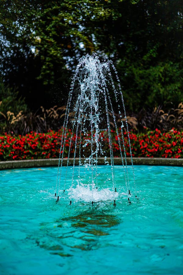A Fountain with a Water Spout Shooting Out of it. Behind are Red ...