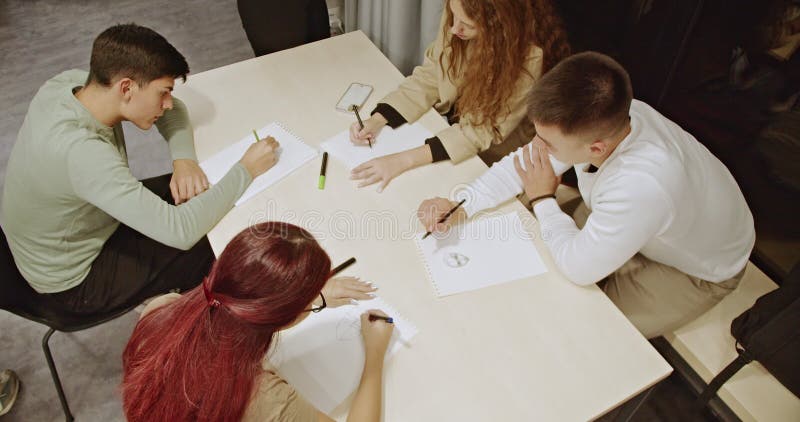 Four Art Students Sketching and Drawing Together at a Table after Class ...
