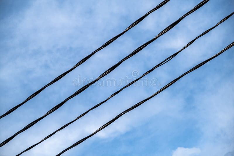 Four Black Electrical Wires Against the Blue Sky. Abstract Background ...